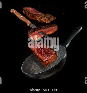 Flying pieces of raw beef steaks from cutting board, isolated on ...