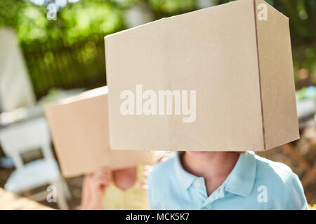 Two children hide their faces under funny painted cardboard boxes Stock ...
