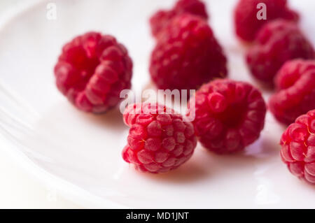 big fresh juicy raspberries on a white saucer close up, selected focus ...