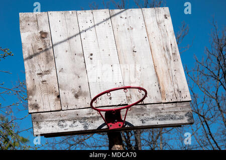 A red basketball hoop without a net, mounted to a backboard. The ...