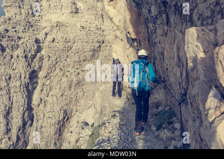 Climbers walking on narrow ledge protected by via ferrata set Stock ...