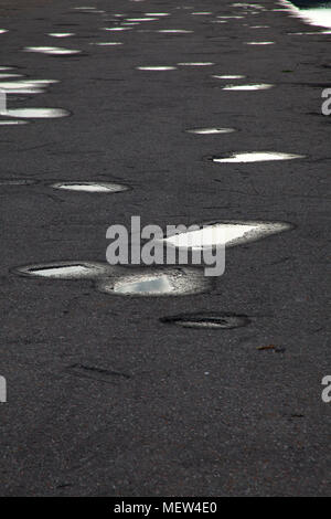 wet bumpy asphalt road with water puddles after rain Stock Photo - Alamy