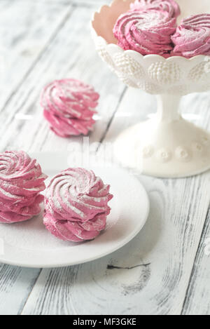 Pink and white marshmallows on a wooden table with kitchen utensils ...