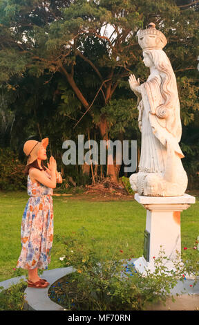 Asian female tourist praying with Virgin Mary statue at Merizo Bell ...