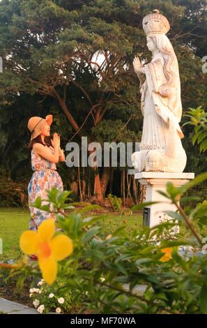 Asian female tourist praying with Virgin Mary statue at Merizo Bell ...