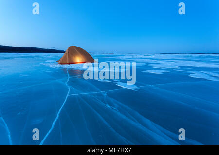 Russia, Amur Oblast, illuminated tent on frozen Zeya River at night ...