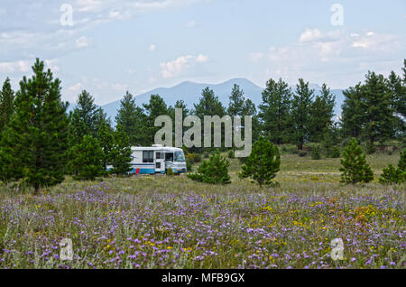 A large Class A motorhome is boondocking in the national forest ...