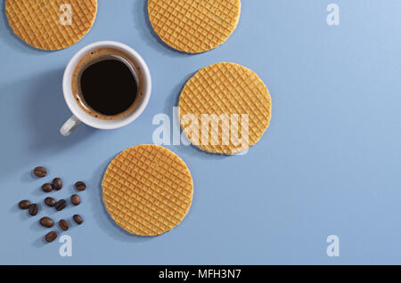 Round wafers and cup of coffee on blue table, top view Stock Photo - Alamy