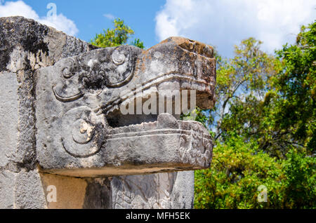 Mayan stone snake head sculpture with the pyramid of Kukulcan in the ...