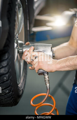 car mechanic screwing or unscrewing car wheel Stock Photo - Alamy