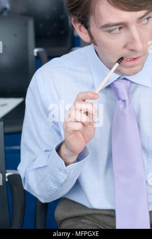 Businessman chewing his pen Stock Photo - Alamy