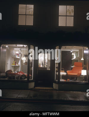 A vertical night view of the exterior of a shop and a parked bicycle ...
