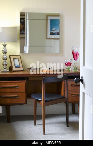 A small study with a mirror above a retro wooden desk and chair with a lamp and decorative vases on display Stock Photo Alamy