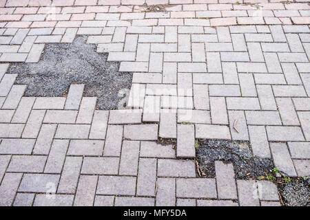 Uneven pathway. Damaged or poor block paving with weeds growing through ...