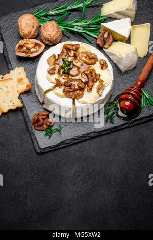 Brie cheese with walnuts, thyme, and rosemary on a black background ...