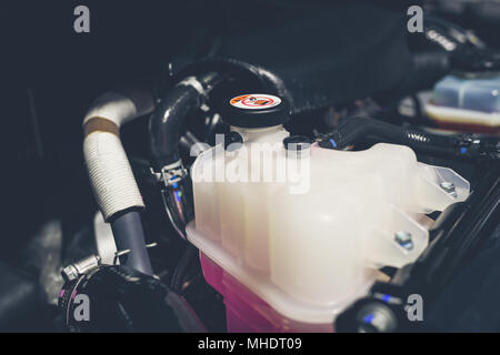 coolant system reservoir cap with warning and manual signs in a car ...