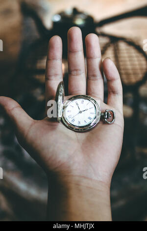 Silver pocket clock in hand on money background. Time is money concept ...
