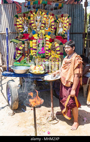 Unidentified brahman man with statues of the Indian gods and offerings ...