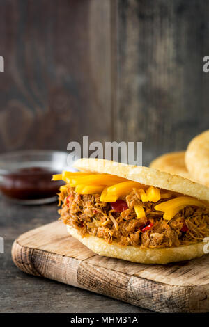 Arepa with shredded beef and cheese on wooden background. Venezuelan ...