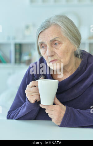 Sad old woman with headache drinking tea Stock Photo - Alamy