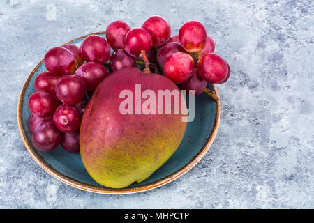Mango and grapes on plate. Studio Photo Stock Photo - Alamy