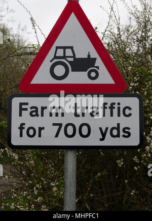 A farm vehicle traffic warning sign on a country road. Farm equipment ...
