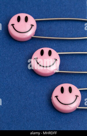 Plastic head metal safety pins pinned in jeans material. Orange smile ...