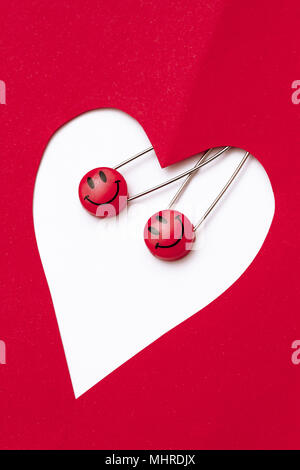 Plastic head metal safety pins pinned in paper. Pink smile emoticon ...