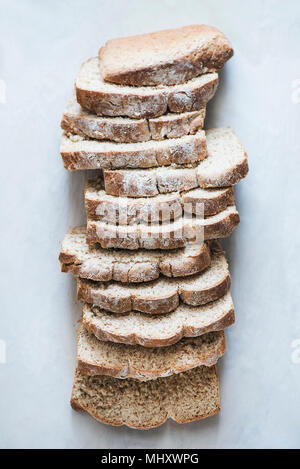 Freshly baked bread slices on cutting board against white wooden ...