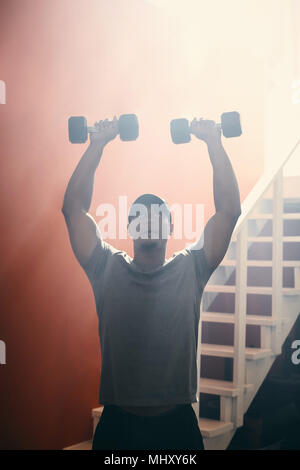 Man using dumbbells in gym Stock Photo - Alamy