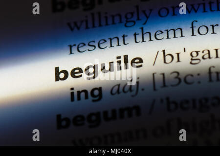 beguile word in a dictionary. beguile concept Stock Photo - Alamy