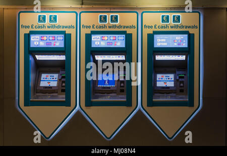 Cash withdrawl automated vending machines in a line, lit from overhead ...