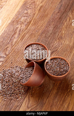 An overturned ceramic clay bowl with linseeds on a brown rustic wooden ...