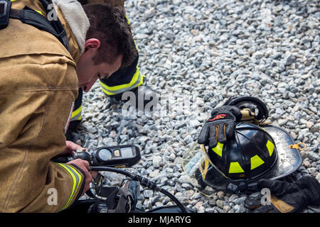 A firefighter checks the air tank on the back of another firefighter ...