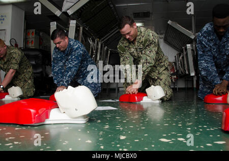 Sailors practice cardiopulmonary resuscitation (CPR) on a training ...