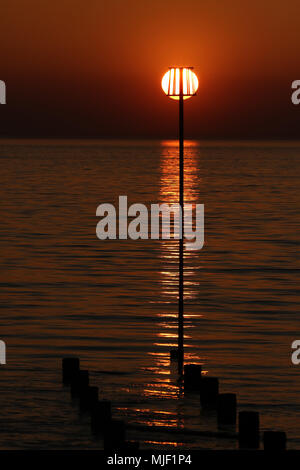 The sun sets behind a sea defence groyne at Heacham, Norfolk, on May 5 ...