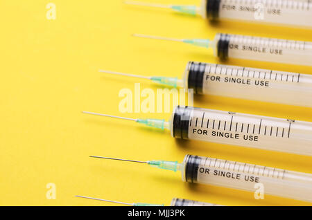 Details of syringes over bright yellow background Stock Photo - Alamy