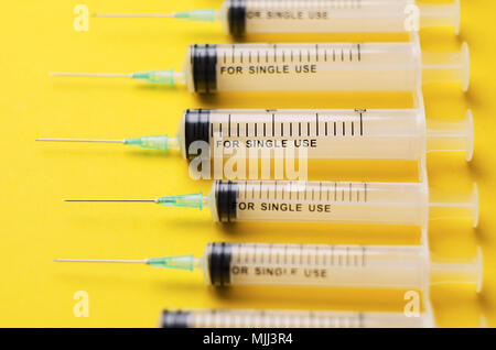 Details of syringes with "for single use" text over bright yellow ...
