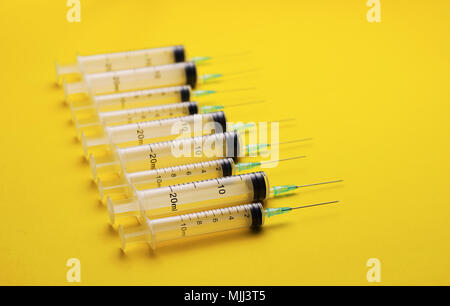 Details of syringes over bright yellow background Stock Photo - Alamy