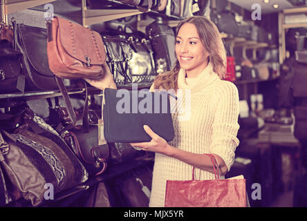 Pretty female choosing bag among assortment in store Stock Photo - Alamy