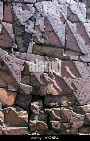 Closeup of geometric fractured rock surface of vertical volcanic dyke ...
