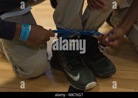 Participants tie their ankles together for a three-legged race during ...