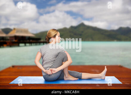 woman making yoga in twist pose on mat Stock Photo - Alamy