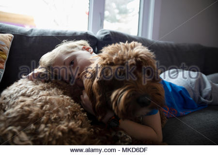 Cute boy cuddling with dog on bed Stock Photo - Alamy