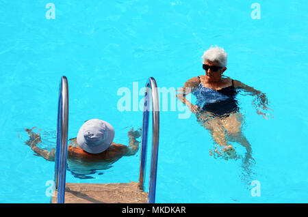 Senior citizens exercise in a swimming pool by walking a set number of ...