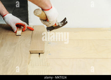Laying hardwood parquet. Worker clamps parquet with a hammer Stock ...