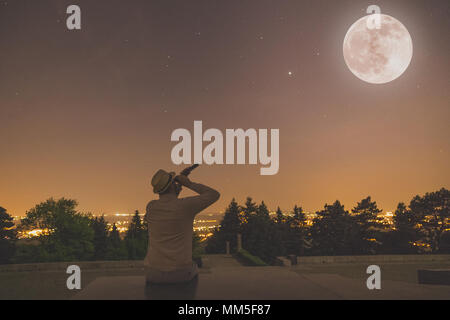 Man looking at full moon with spyglass Stock Photo - Alamy