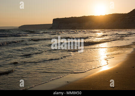 Waves approaching beach sand during golden sunset Stock Photo - Alamy