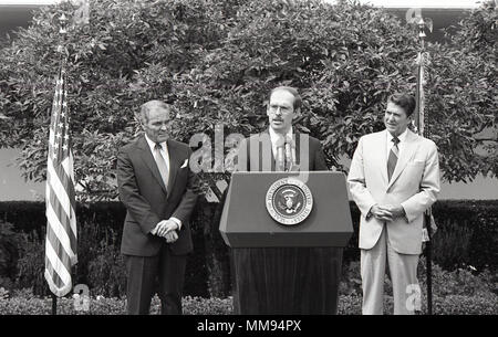 A MAN AT THE PODIUM GIVING A SPEECH WITH RONALD REAGAN AND ANOTHER MAN ...