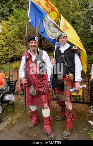 Two men in traditional clothing stand in front of an Eid Mubarak ...